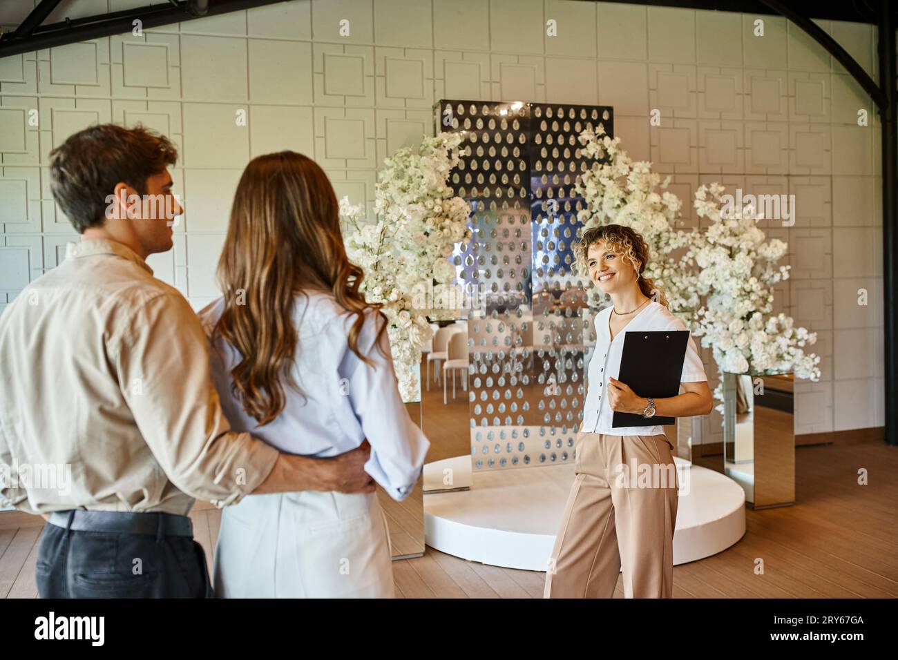 happy event manager with clipboard showing wedding venue with white ...
