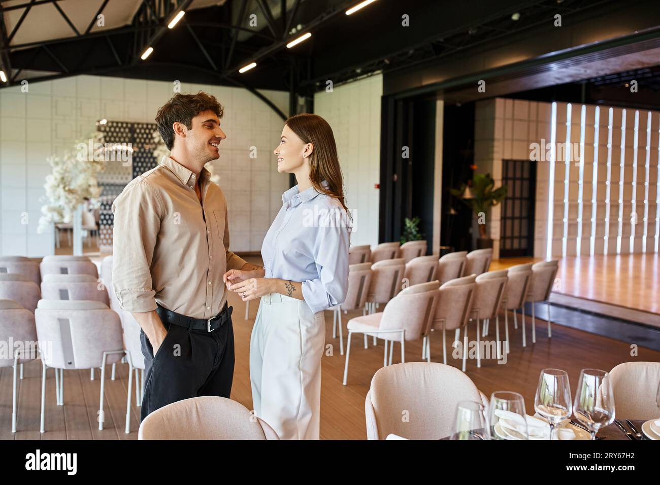 smiling couple talking near festive table with banquet setting in event ...