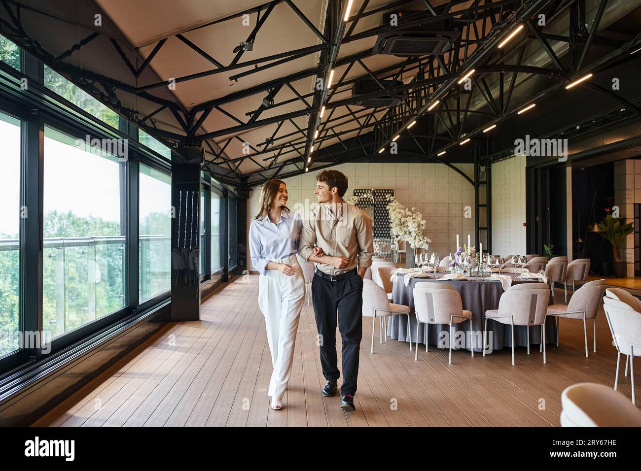 cheerful couple walking along banquet hall with festive tables and ...