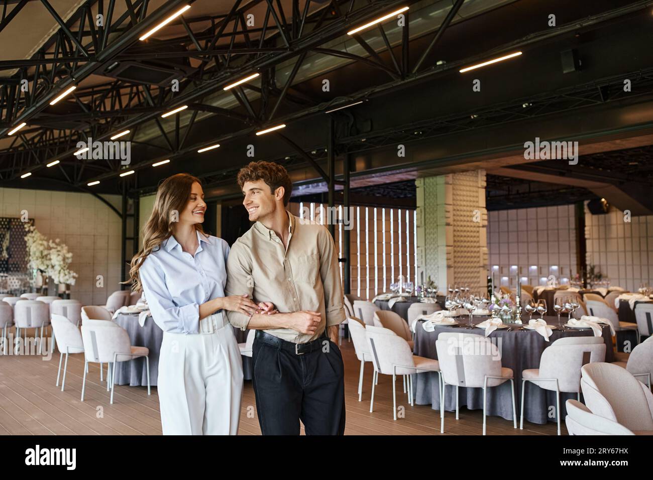happy romantic couple smiling at each other in modern banquet hall with ...