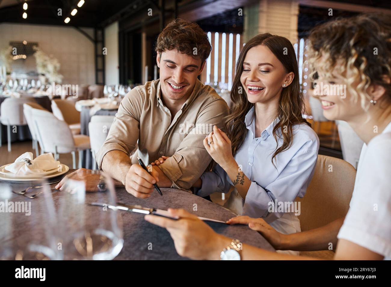 positive couple signing contract with smiling event manager at festive ...