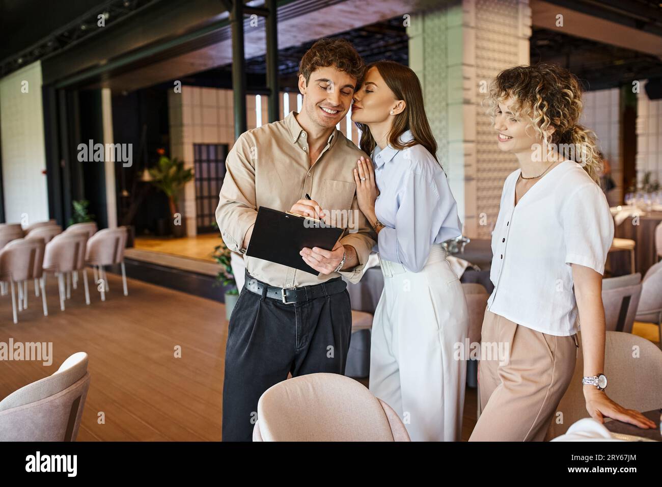 happy young woman kissing boyfriend signing contract with event manager ...