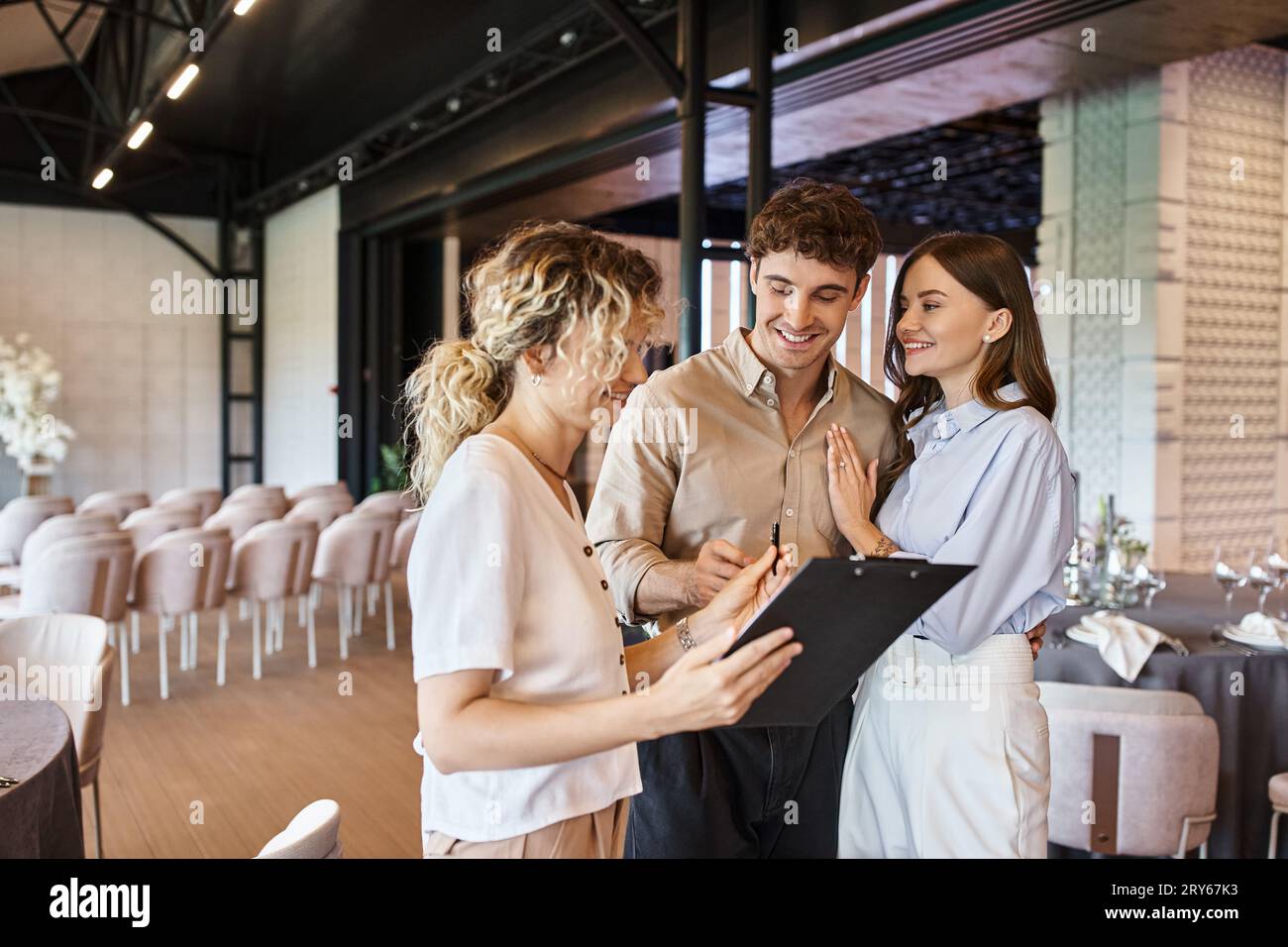 event coordinator giving clipboard with contract to happy couple in ...