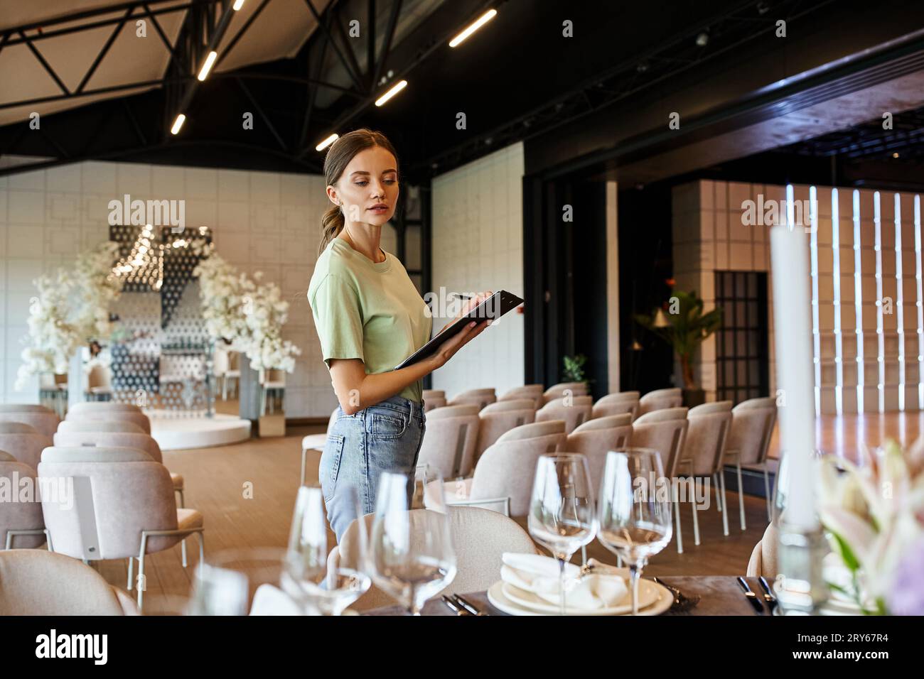 young event manager with clipboard looking at table with festive ...