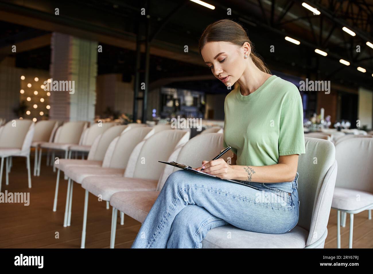 concentrated event manager making notes on clipboard while sitting in ...