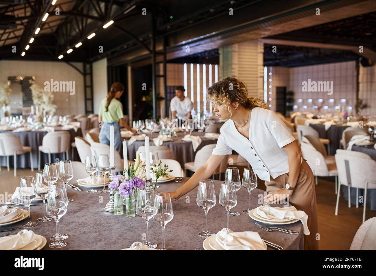 banquet decorator arranging table setting near colleagues working in ...