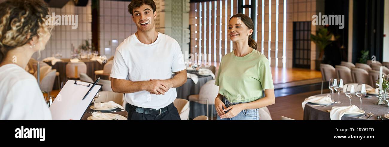 positive event managers smiling near team lead and festive tables in ...