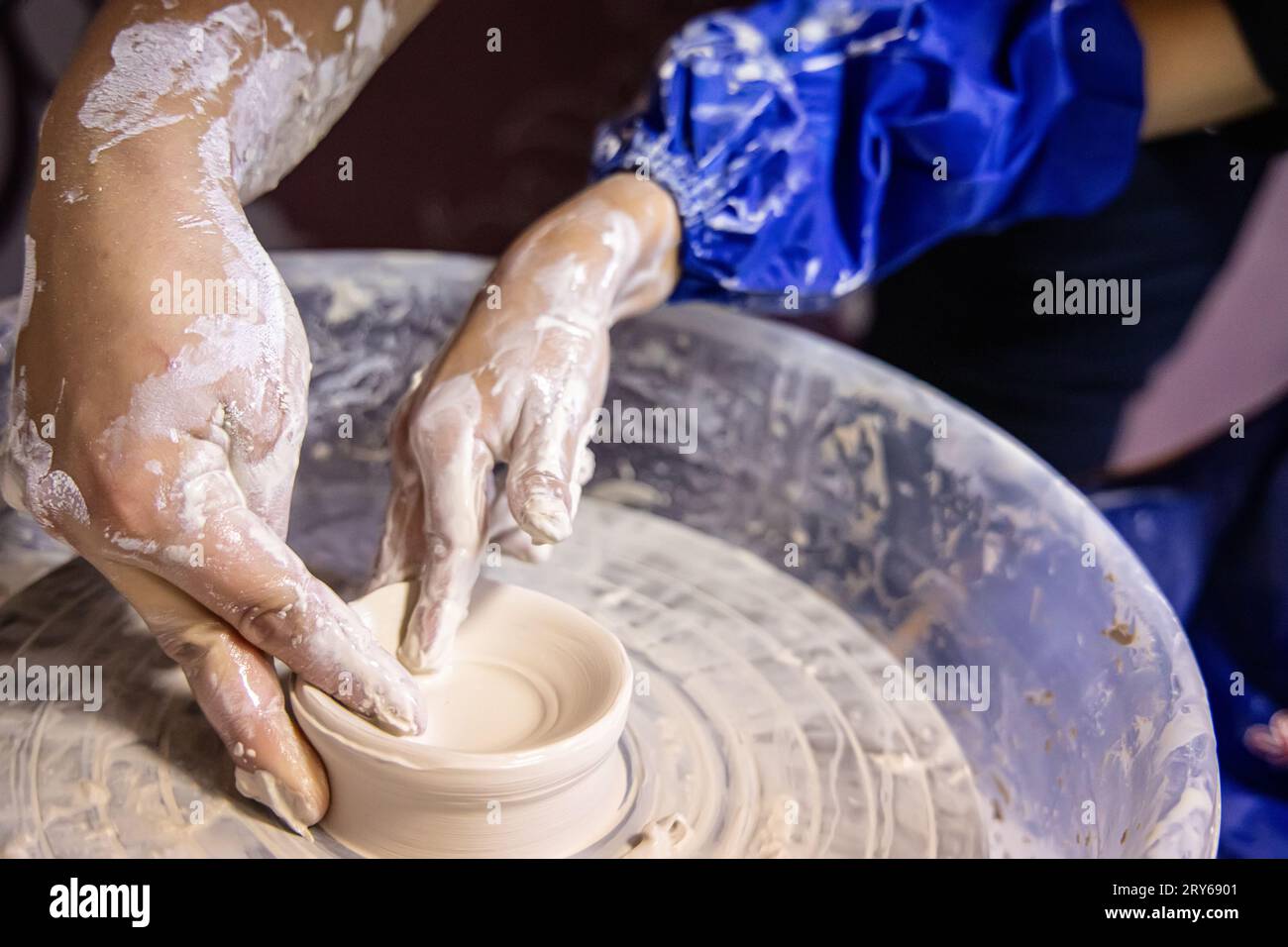 The hands of a teacher teaching how to make a plate on a potter's wheel ...