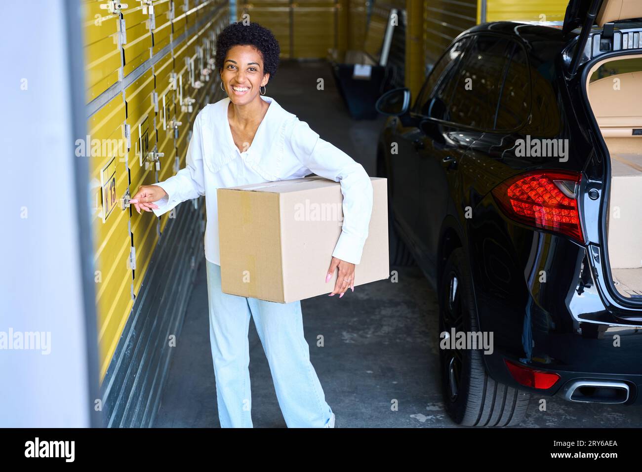 Young woman with a cardboard box opens a storage unit Stock Photo - Alamy