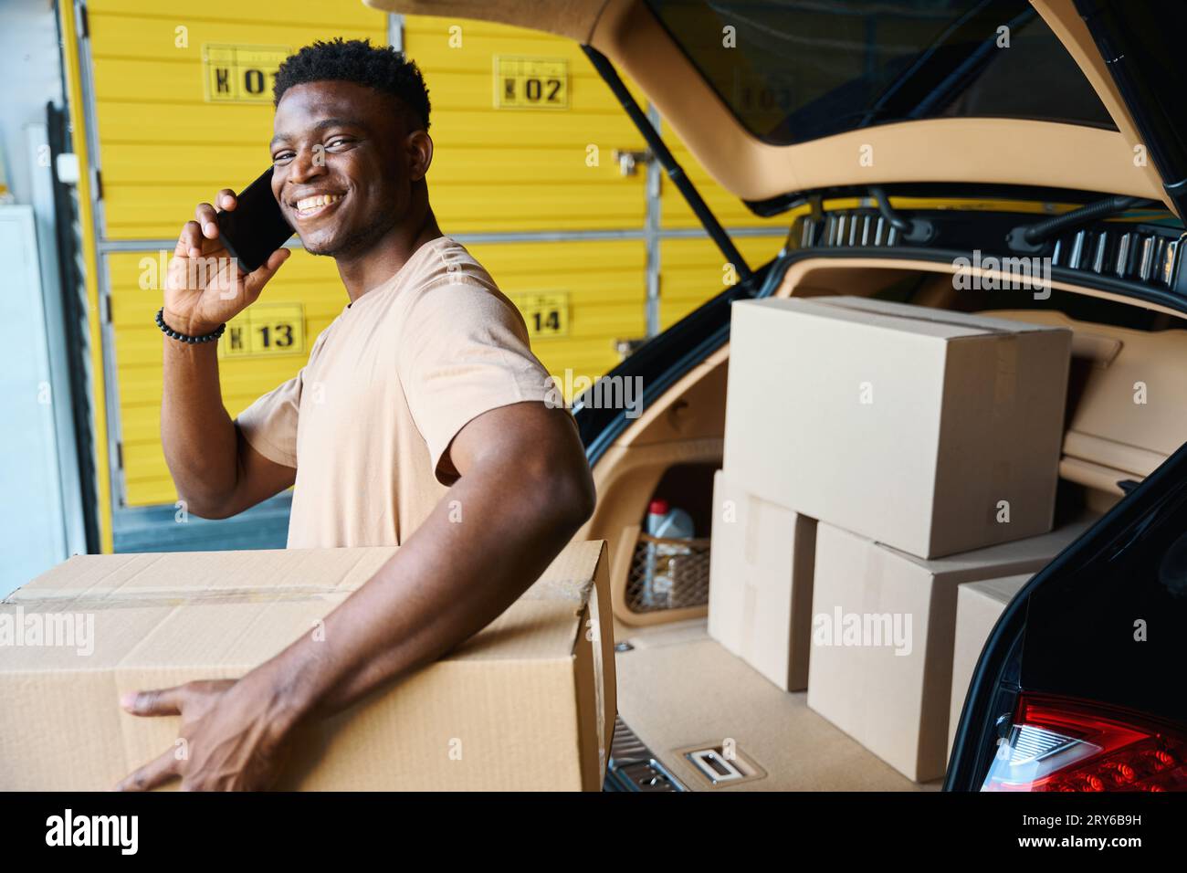 Nice African American guy unloads trunk of car Stock Photo - Alamy