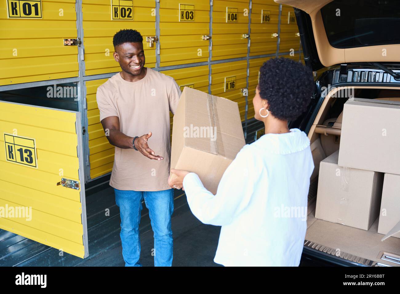 African American guys load boxes with things into yellow cells Stock ...