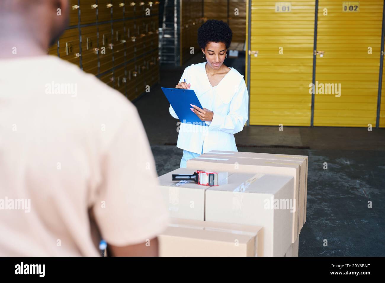 African American manager makes inventory of cardboard boxes being ...