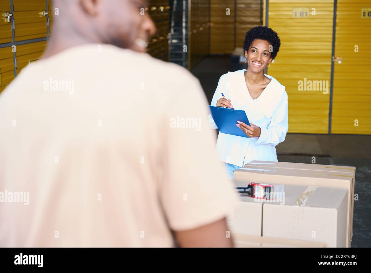 Manager at warehouse makes inventory of cardboard boxes being deposited ...