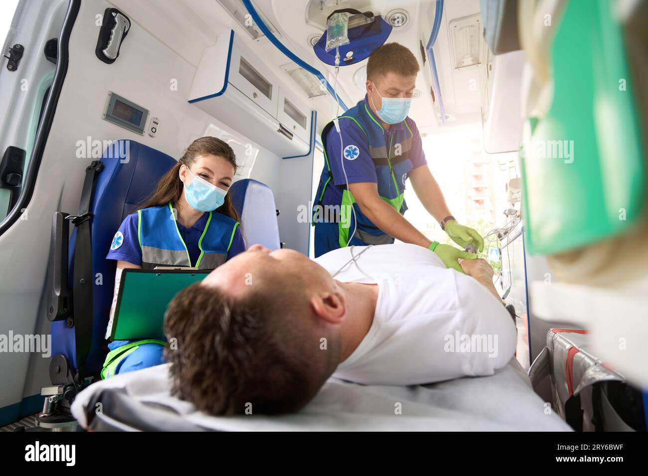 Paramedics transport a patient under a drip in an ambulance Stock Photo ...