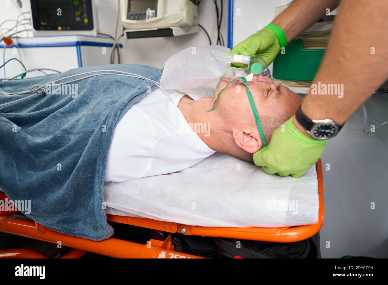Man in protective gloves puts oxygen mask on patient in ambulance Stock ...