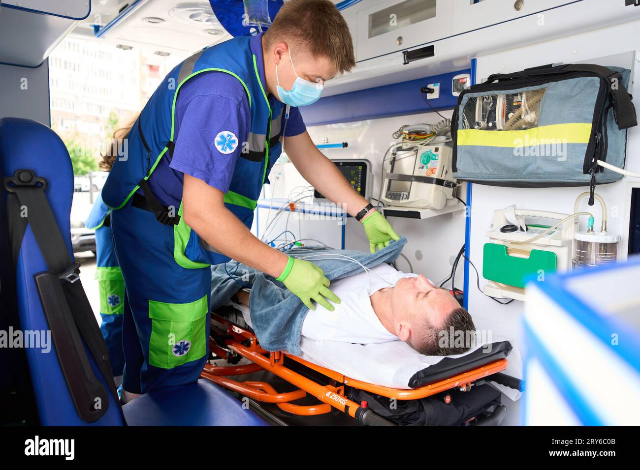 Man in protective gloves covers patient with soft blanket in ambulance ...