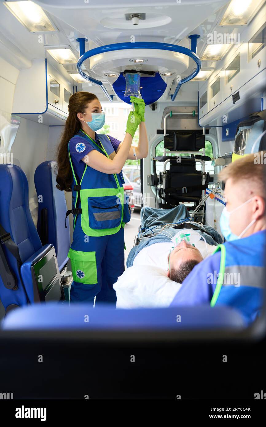 Female doctor puts an IV on patient in an ambulance Stock Photo - Alamy