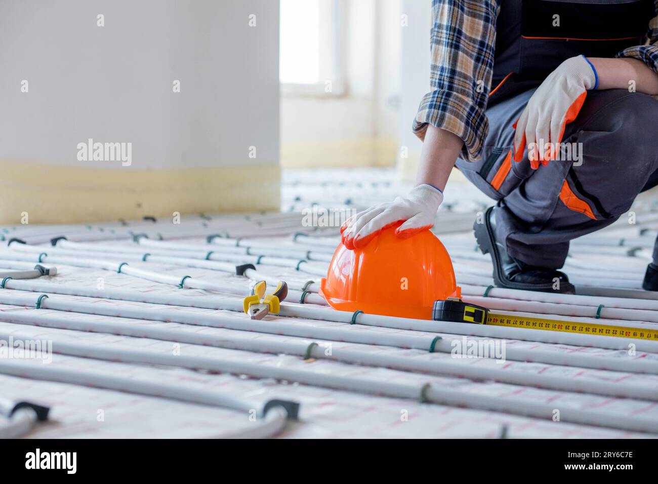 Worker near tools for repair hard hat, plier, glove on warm floor ...