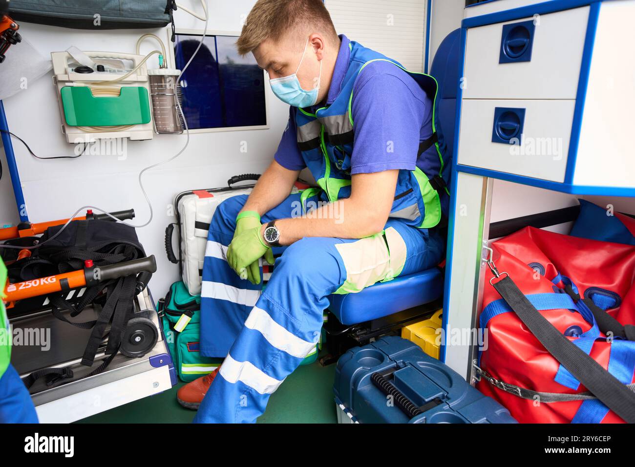 Tired paramedic in a protective mask sits in an ambulance Stock Photo ...