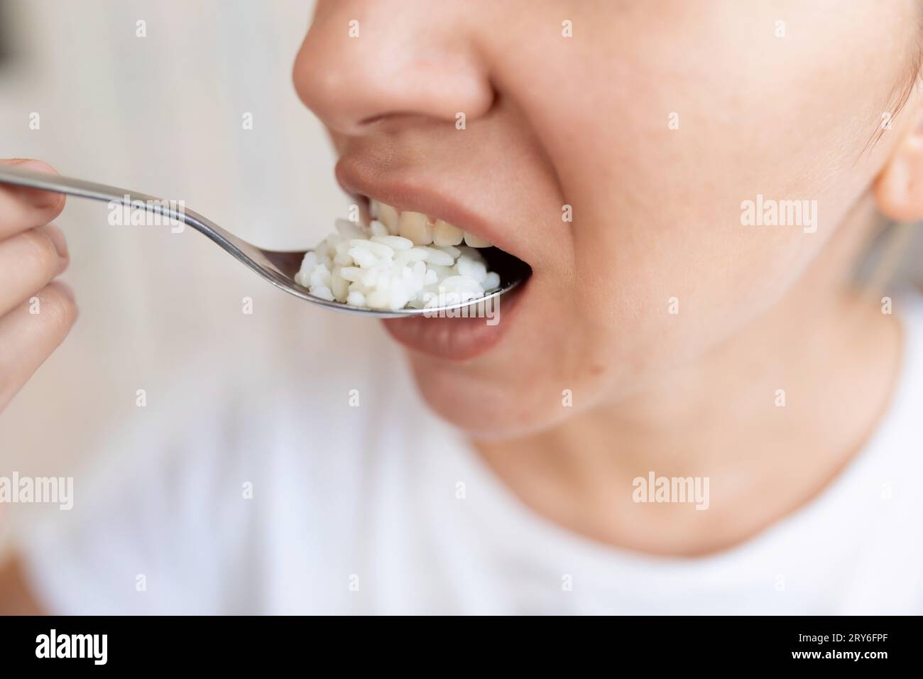 the woman is hungry and therefore eats rice with spoons Stock Photo - Alamy