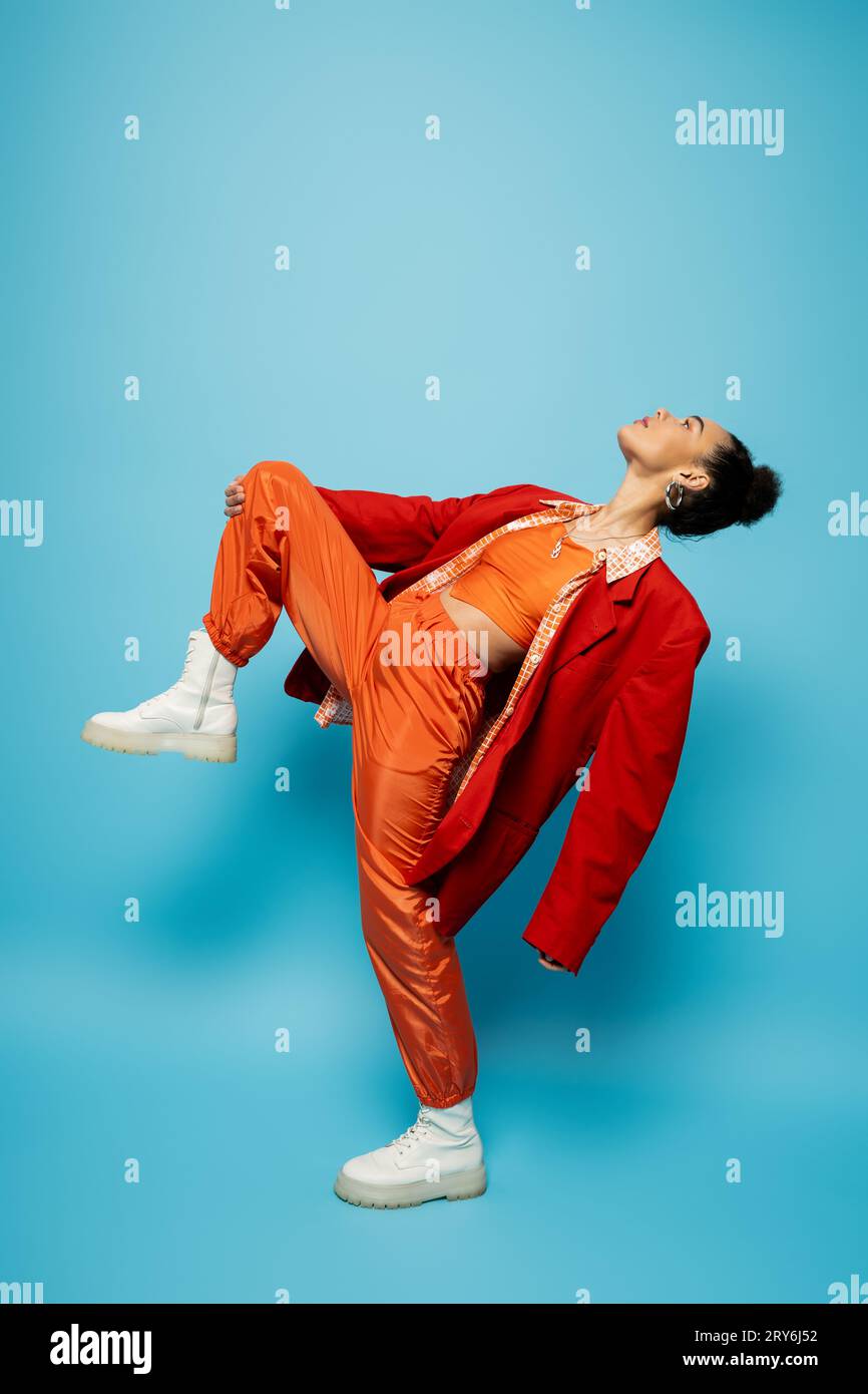 dynamic pose, african american fashion model in vibrant attire on blue ...