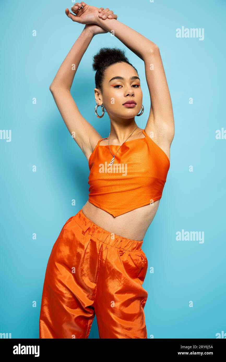 elegant african american woman in bright orange street outfit posing ...