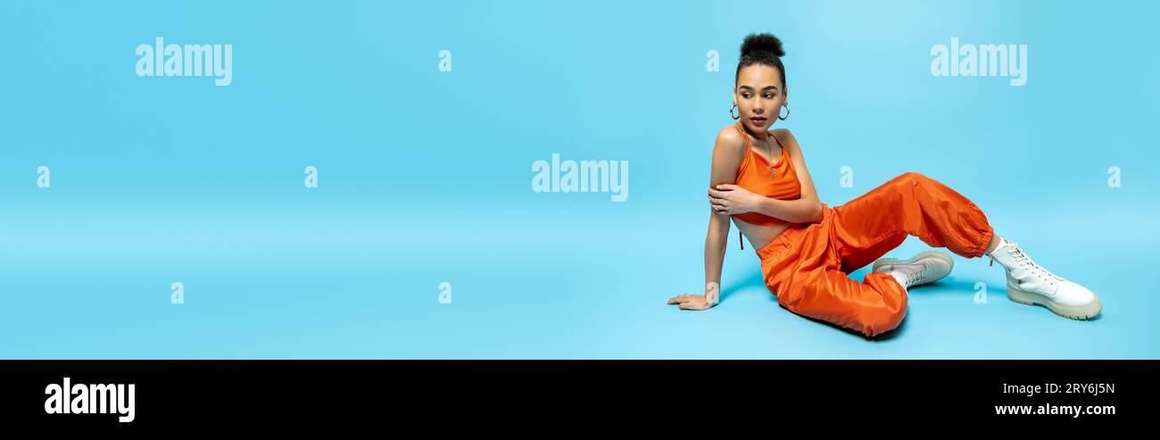 stylish african american woman in urban orange outfit with accessories ...