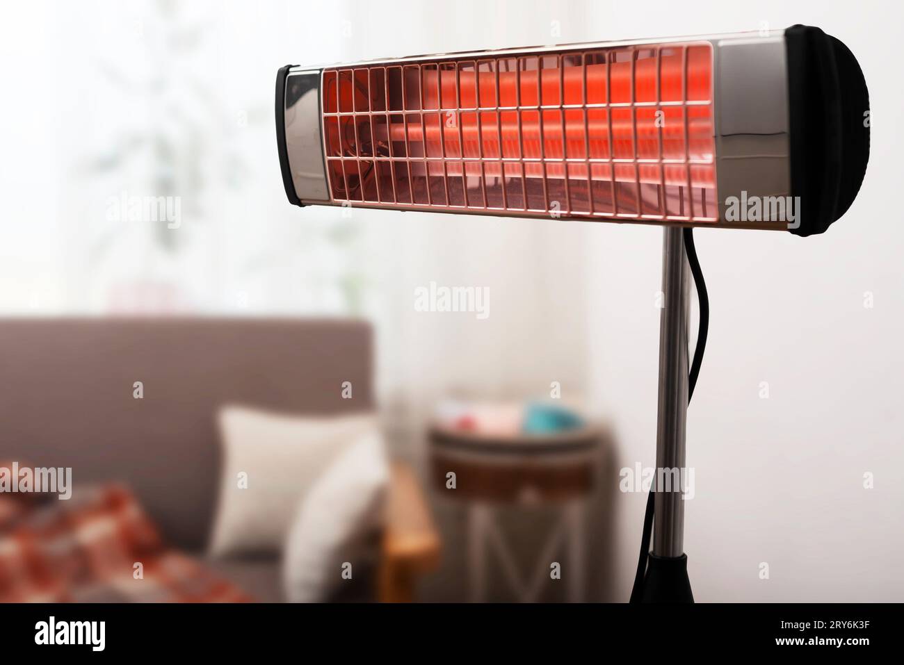 Electric infrared heater warming up living room with sofa and potted ...