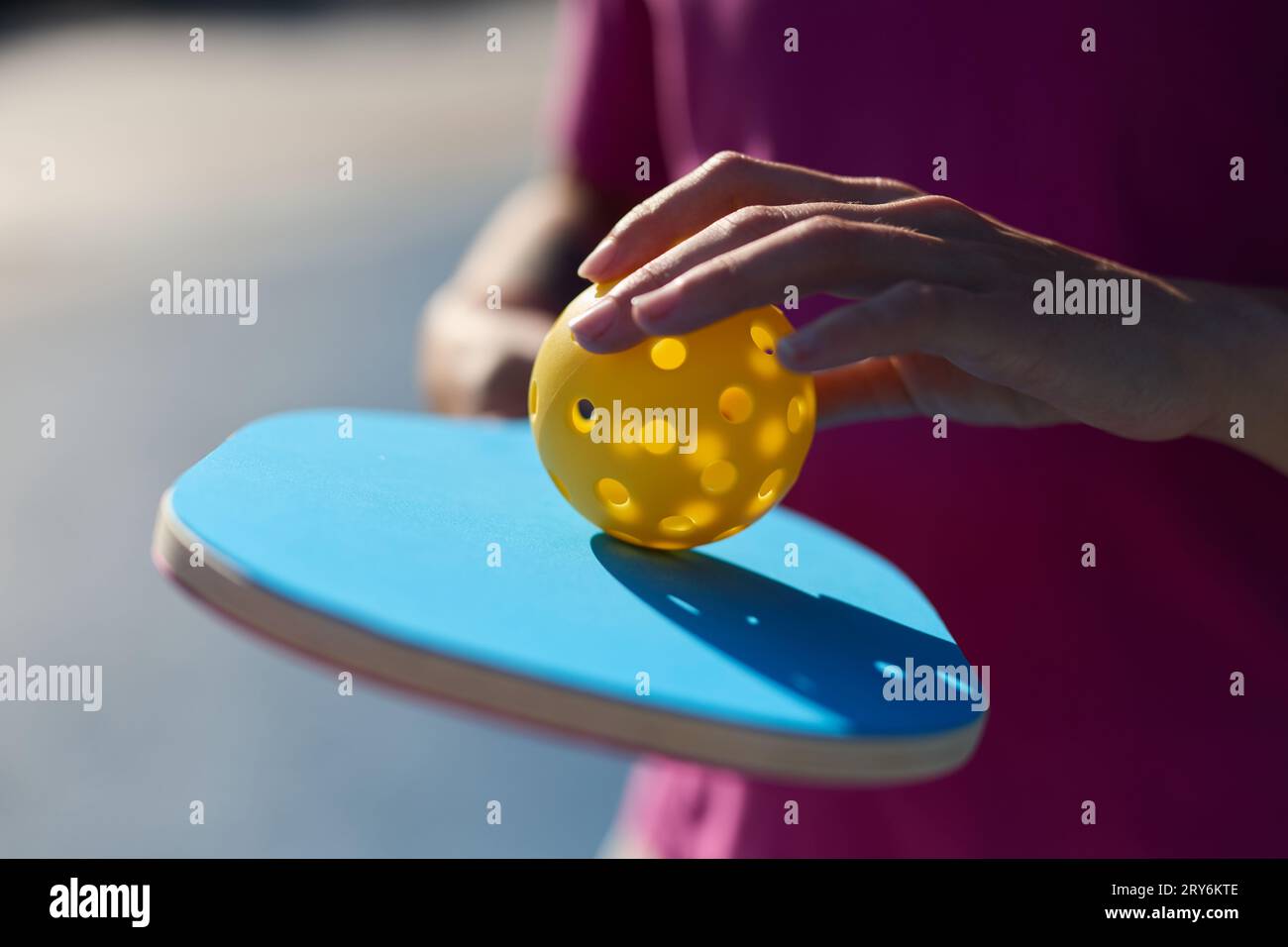 Pickle ball athlete holding a racket and a perforated plastic ball in ...