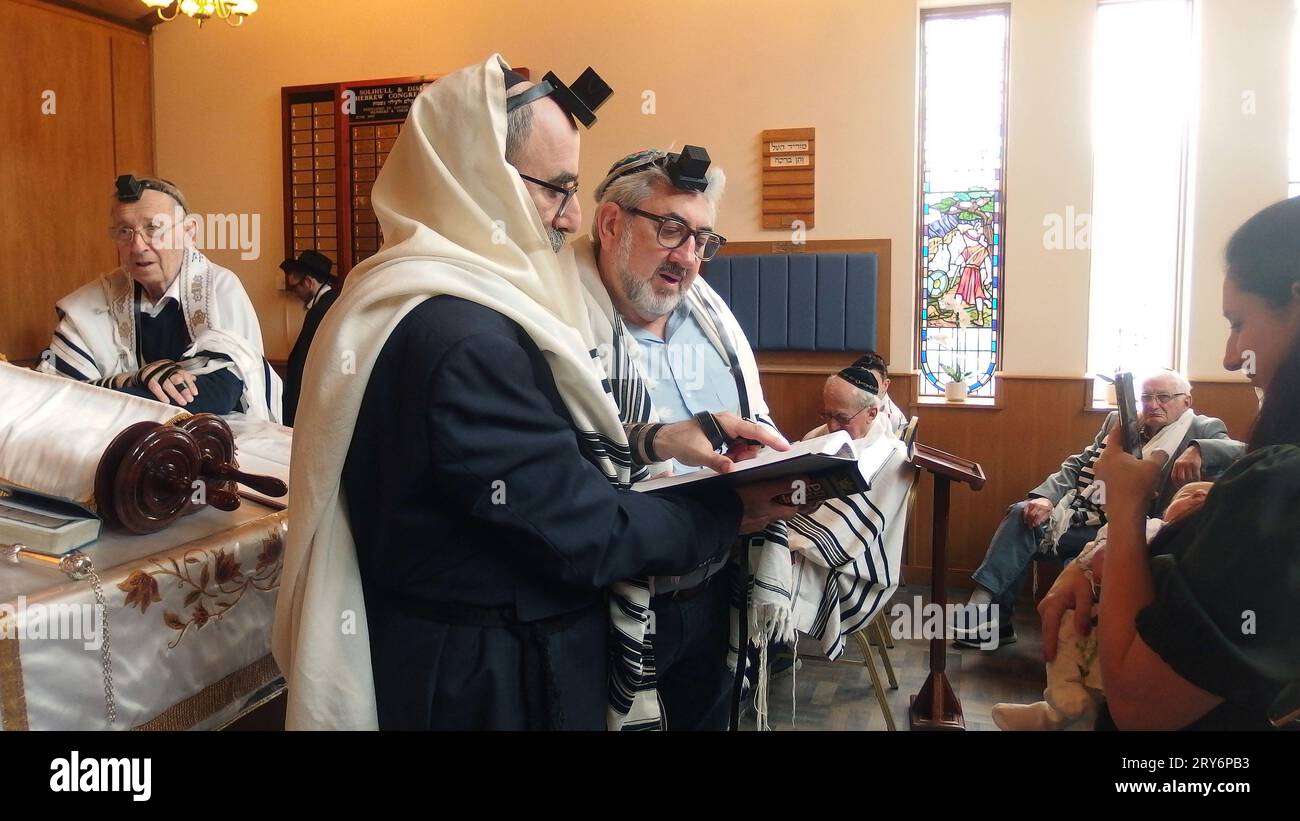 A grandfather is called up to read the Torah by the rabbi during a ...