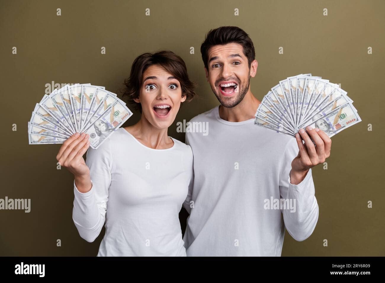 Photo of pretty excited married couple wear white shirts showing money ...