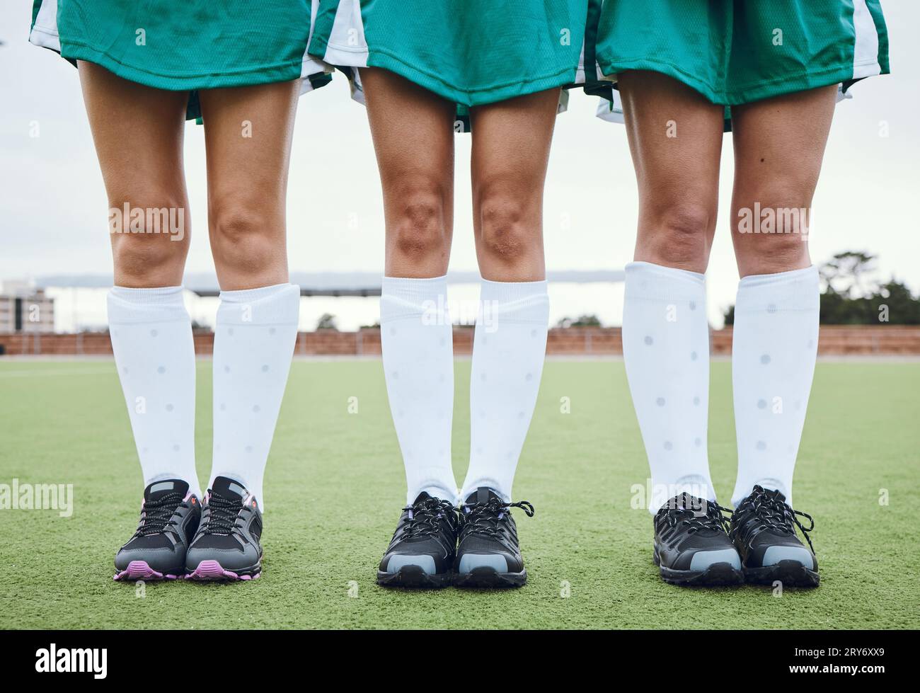 Legs, feet and a woman hockey team outdoor on a field for a game or ...