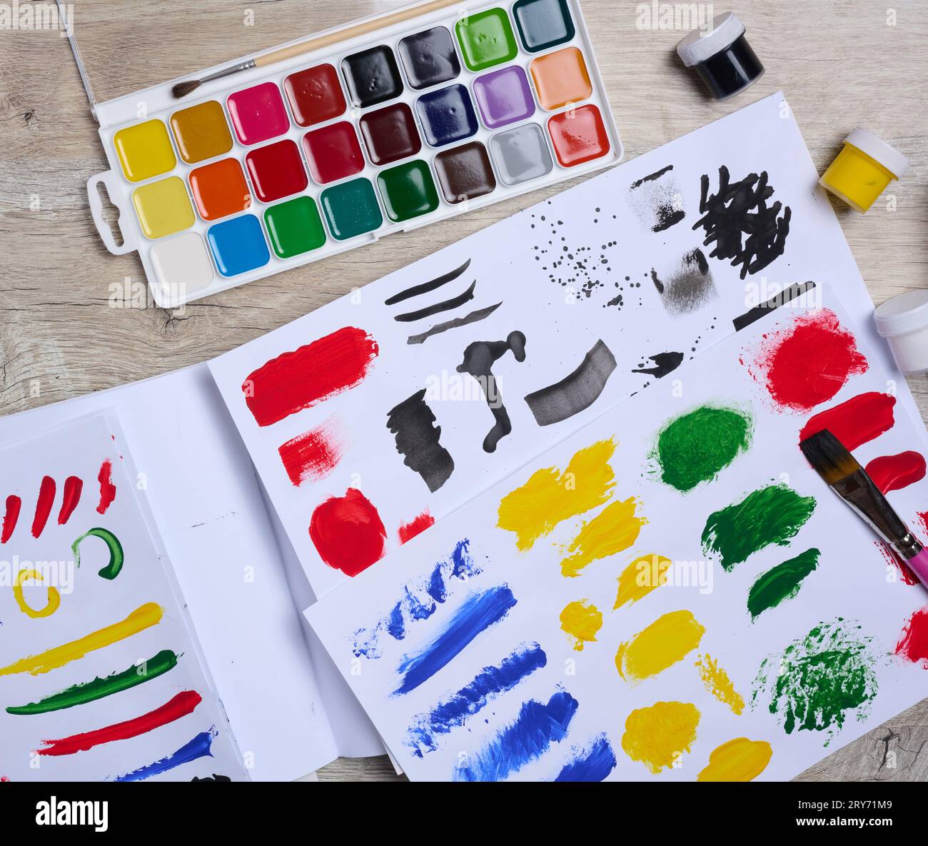 Set of watercolor paints, brushes and paper with different strokes and ...