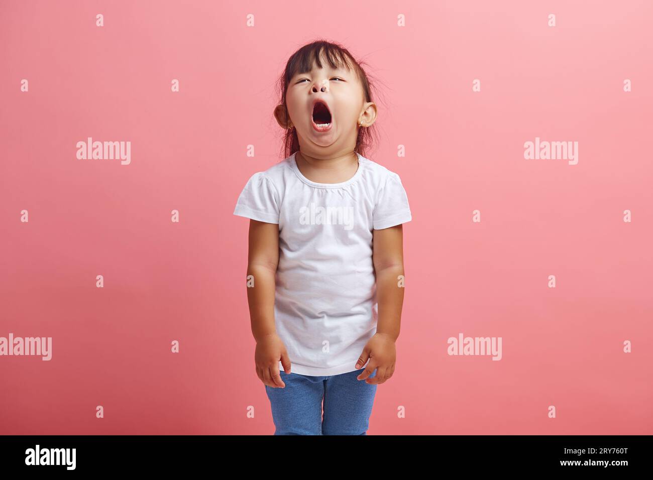 Tired sleepy little girl yawns has exhausted look dressed in white t ...