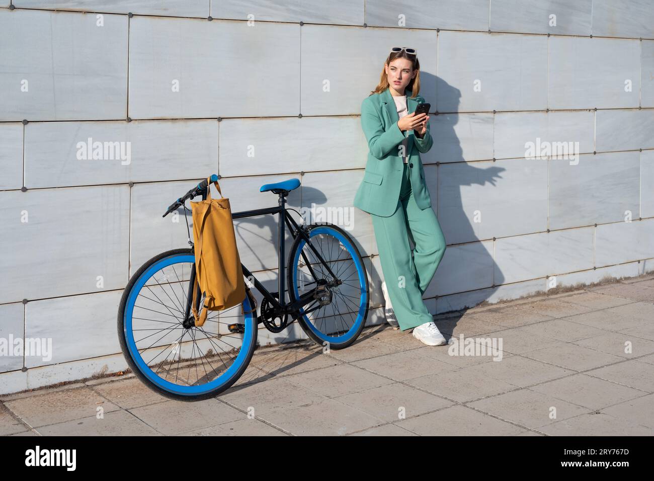 Young empowered ginger-haired woman in green suit using smartphone ...