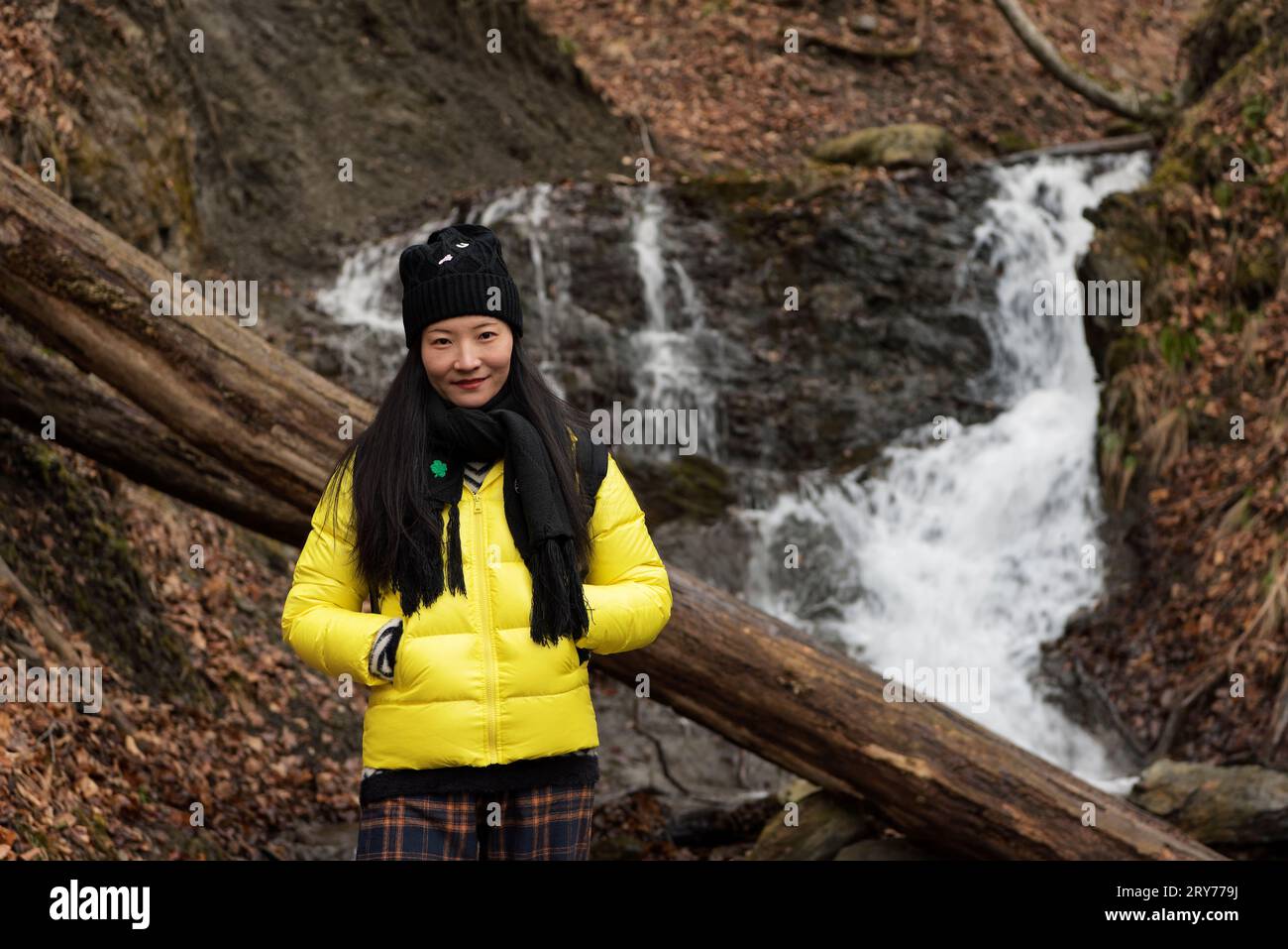 A chinese woman wearing a winter jacket near a waterfall at Rudd Pond ...