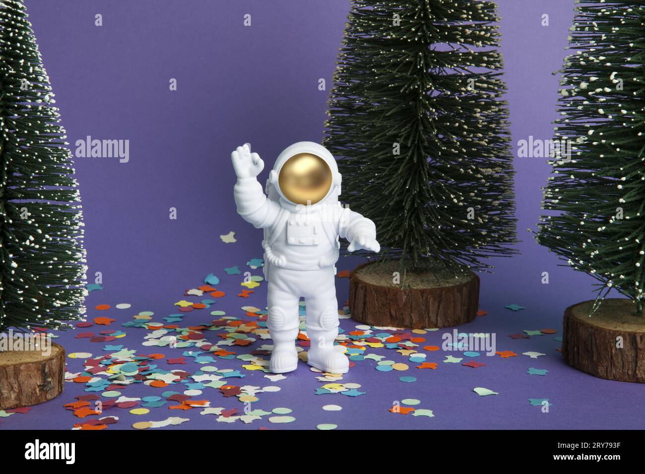 an astronaut figurine in a spacesuit exploring a forest of snowy fir ...