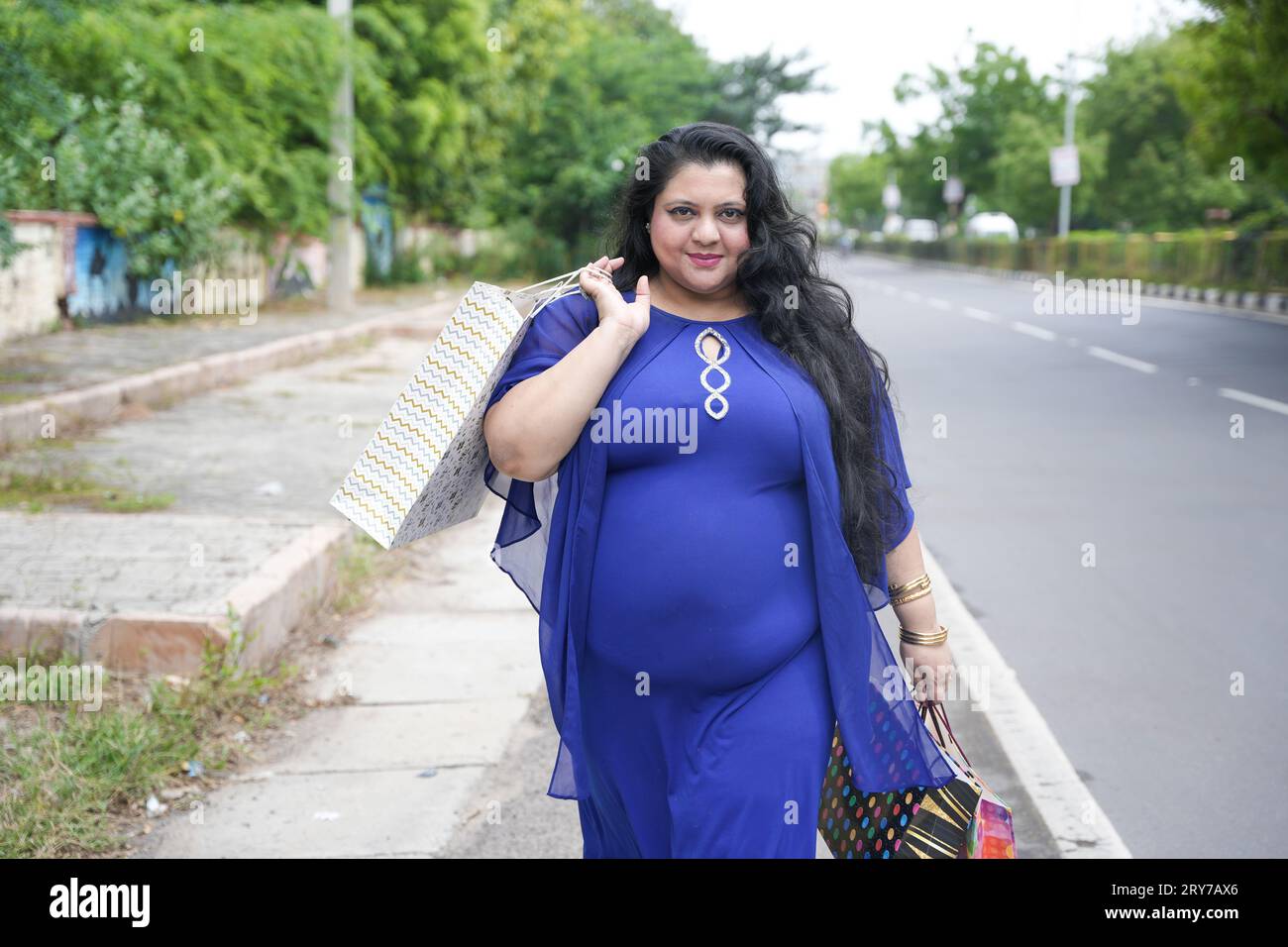 Young indian plus size woman holding shopping bags walking outdoors on ...