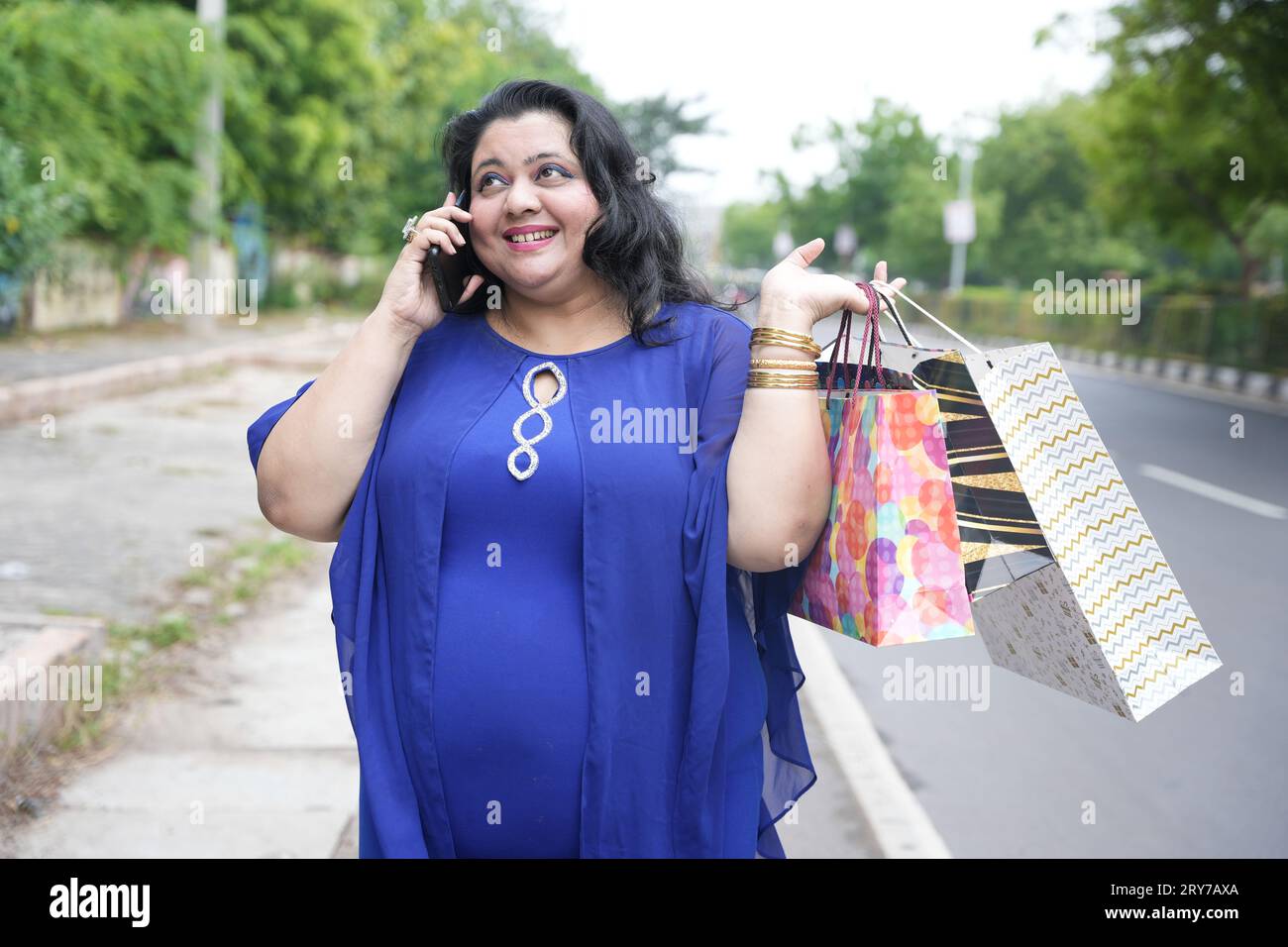 Young indian plus size woman holding shopping bags walking outdoors on ...