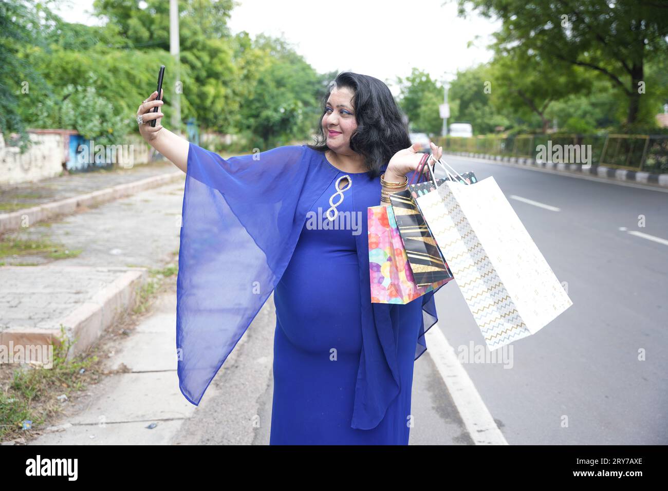 Young indian plus size woman holding shopping bags taking selfie ...