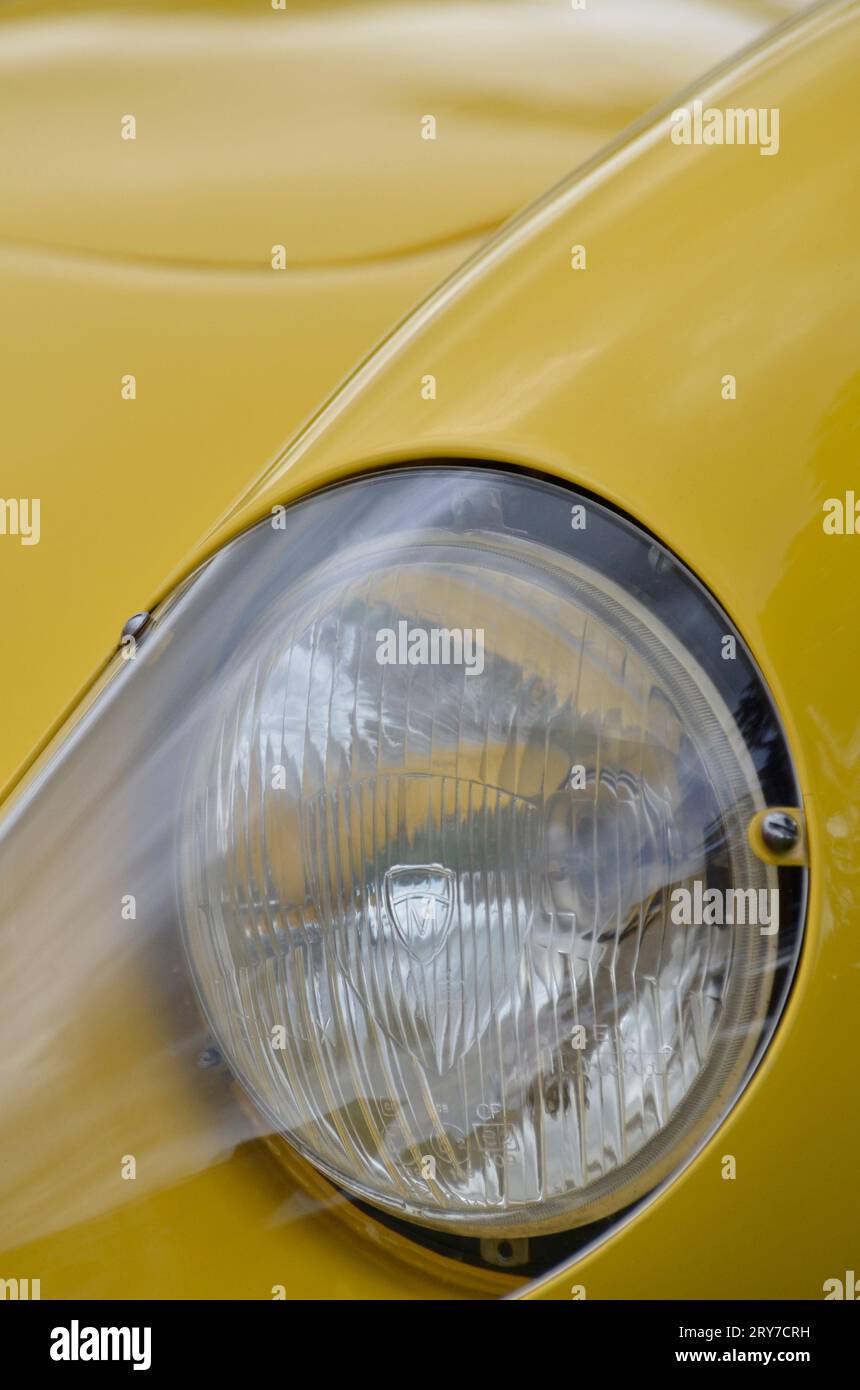 classic bright yellow sports car headlight close up with perspex cover ...