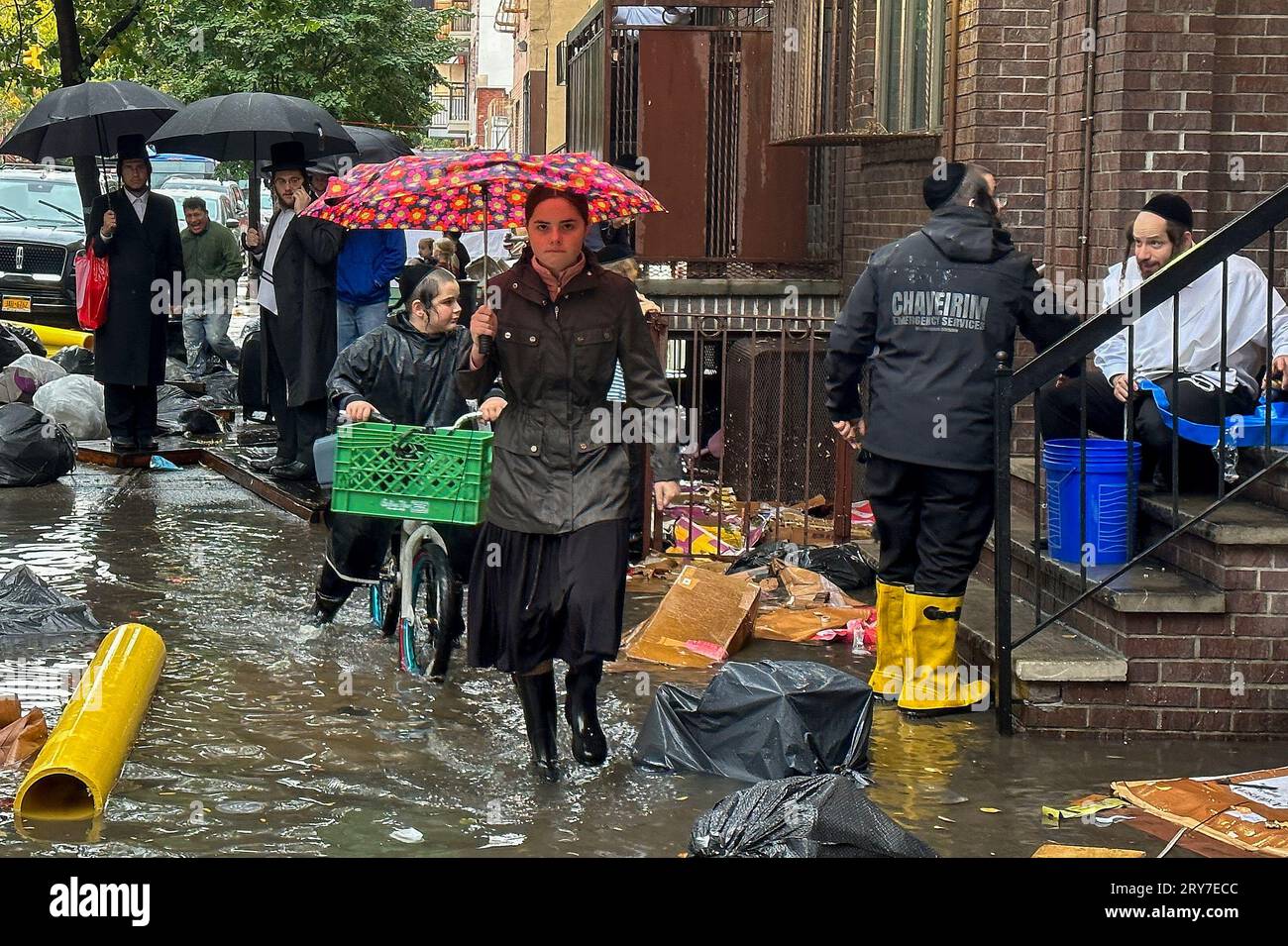 Pedestrians walk along a flooded sidewalk, Friday, Sept. 29, 2023, in ...