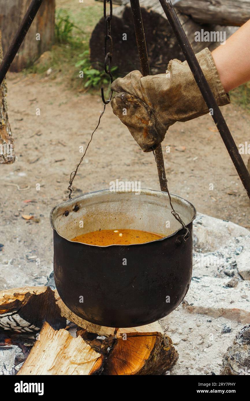 Hand of unrecognizable man wearing glove hanging metal cauldron on hook ...