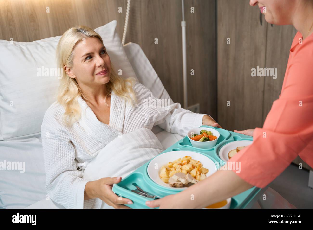Nurse serves tray of food to woman on hospital bed Stock Photo - Alamy