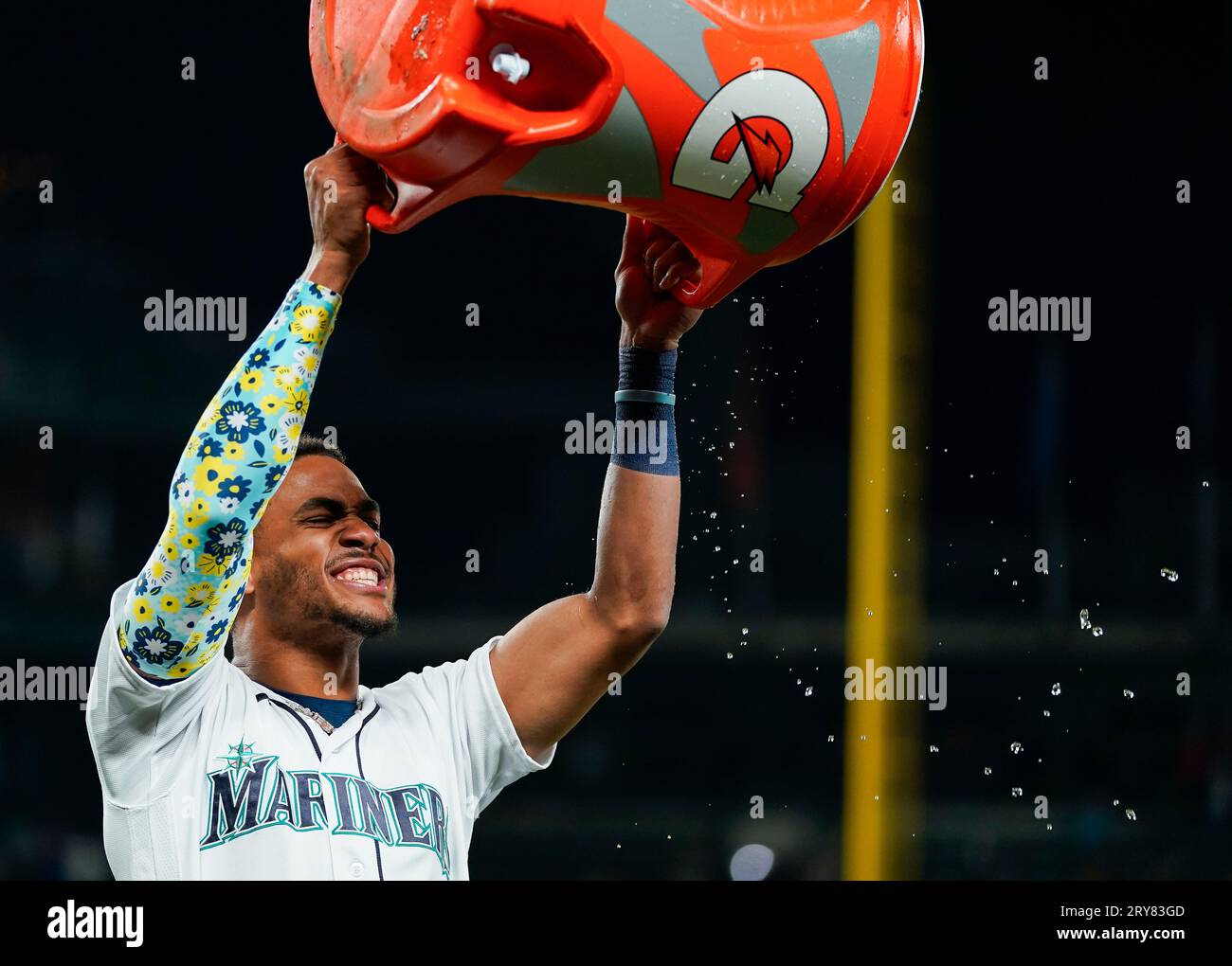 Seattle Mariners' Julio Rodríguez holds up a water bucket after dousing ...