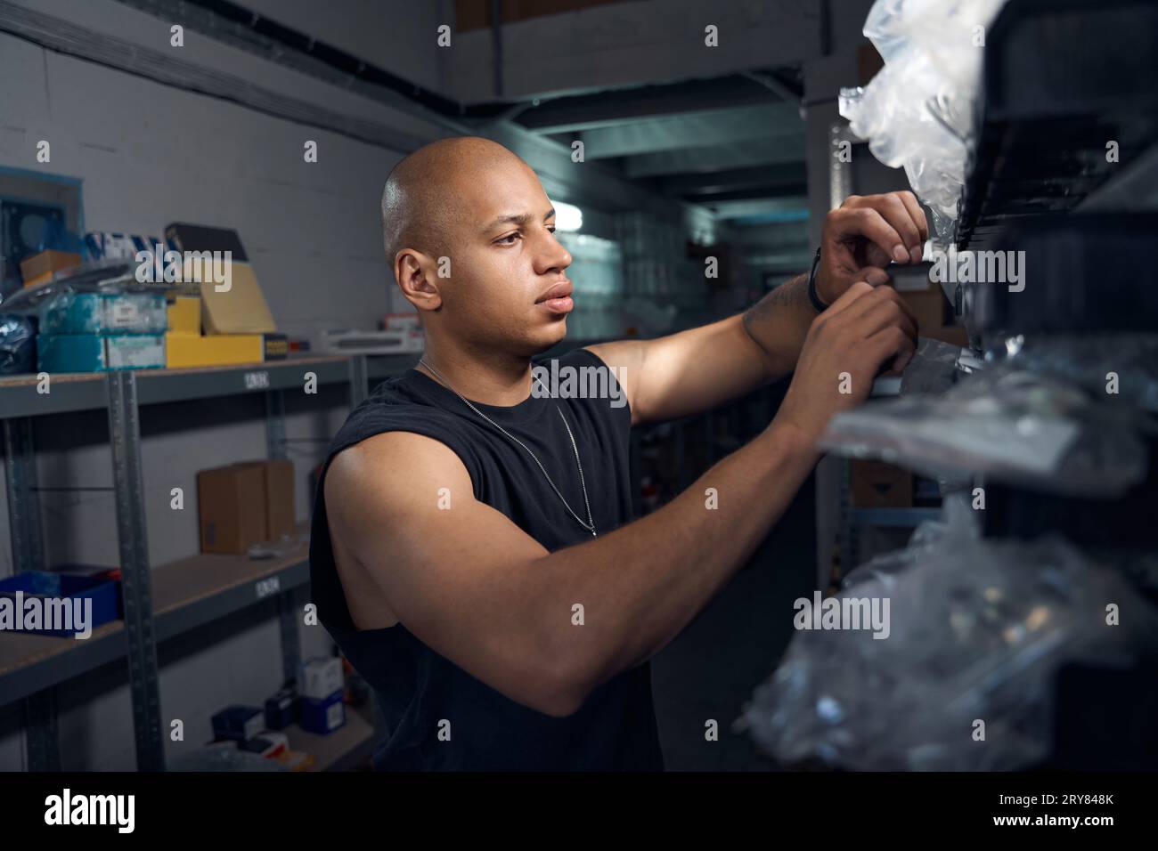 Car repair shop worker checking presence of spare parts in warehouse ...