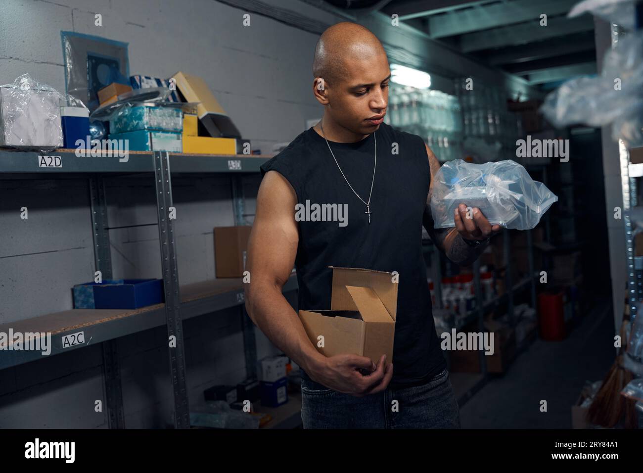 Worker of warehouse checking model of spare part before selling Stock Photo - Alamy