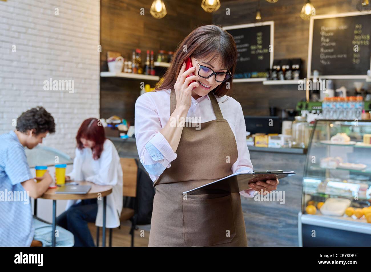 Portrait of middle aged woman coffee shop worker talking on cell phone ...