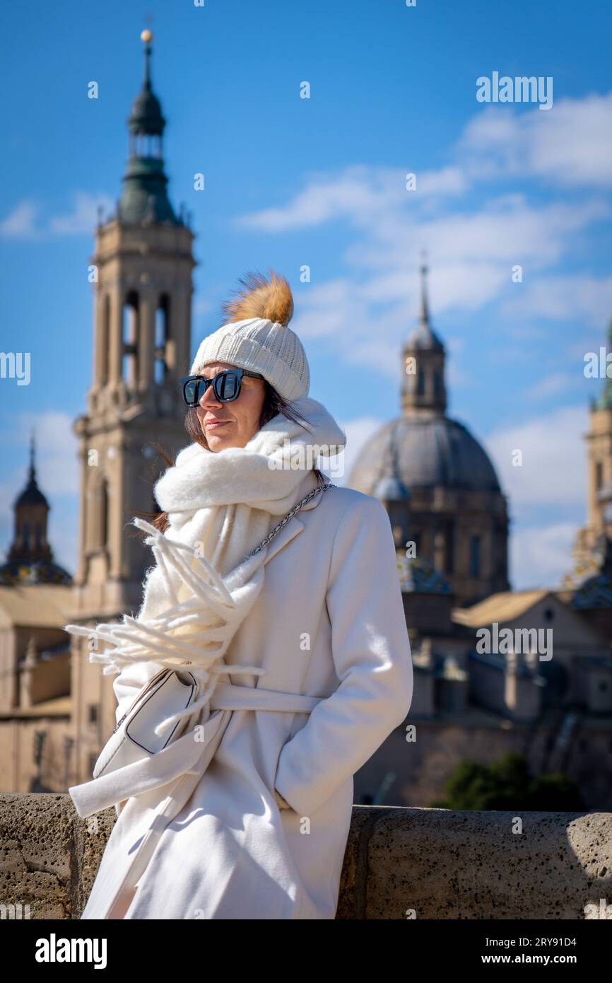 Young woman with coat and white hat on the Stone Bridge with El Pilar ...