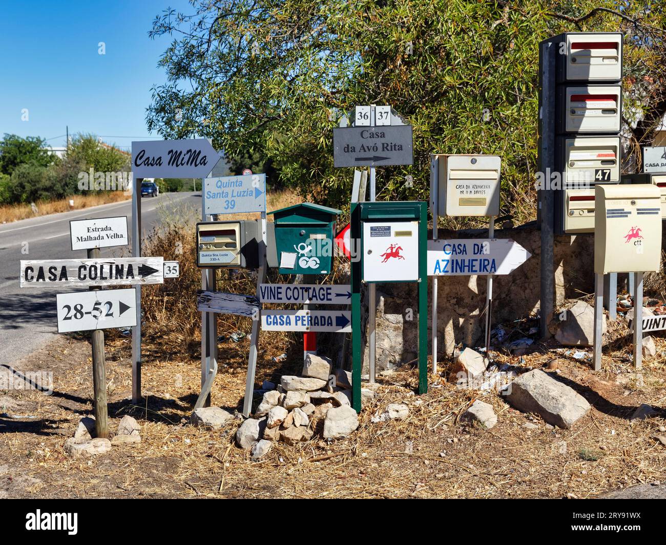 Many different letterboxes and signs are jumbled up on the side of the ...